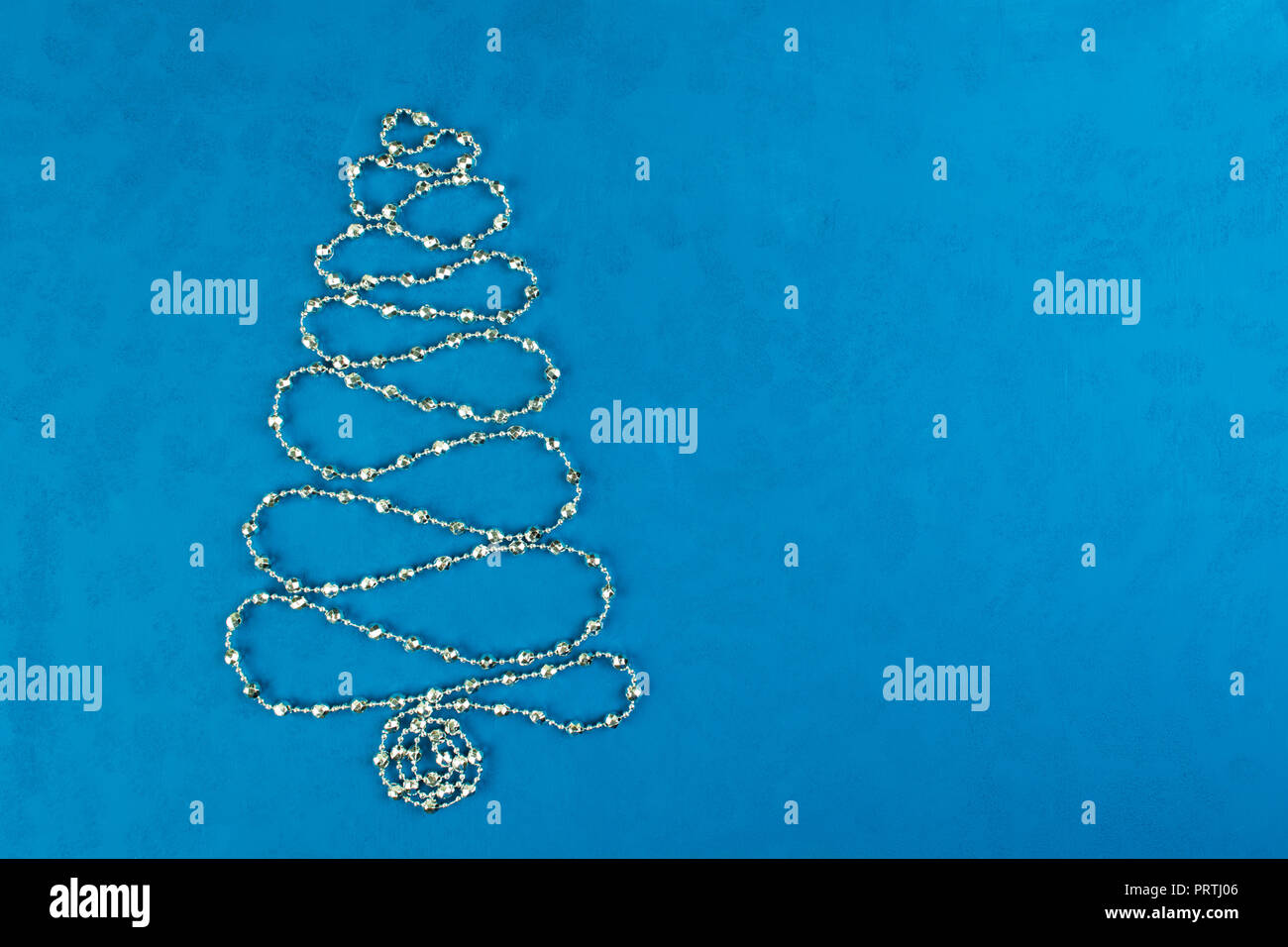 Christmas decoration tree of silver shine garland over blue background ...
