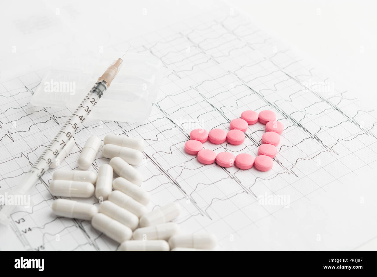 Heart of pills and syringe on paper cardiogram Stock Photo - Alamy