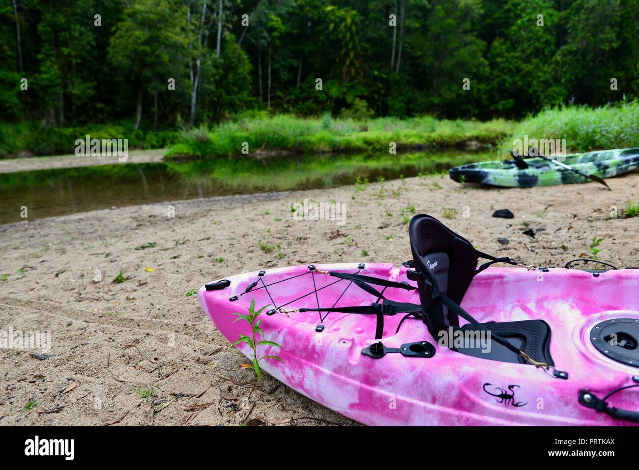 Pink sit on top kayak on the sand next to a river, no people, South ...