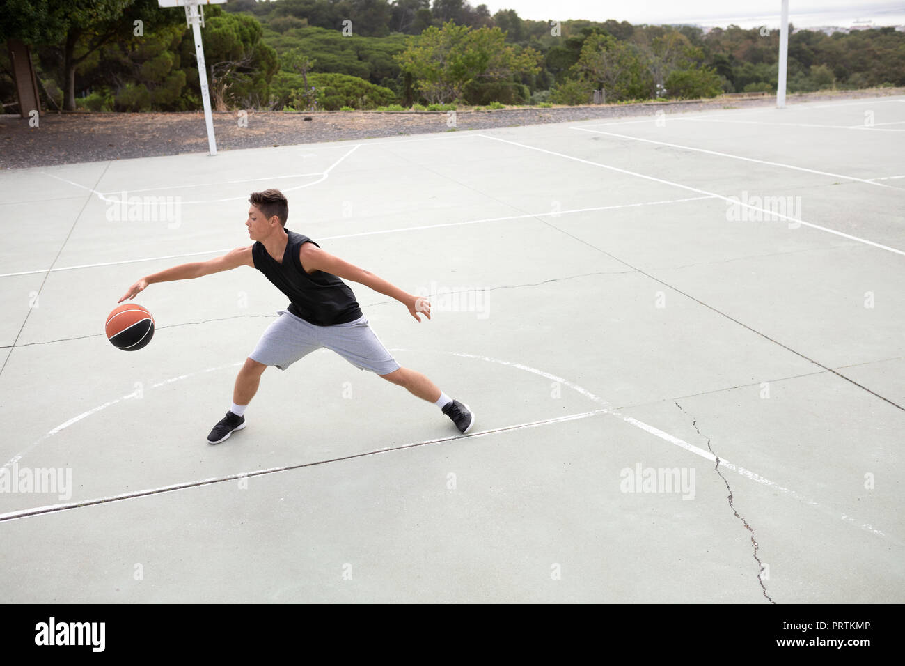 Male teenage basketball player practicing on basketball court Stock ...