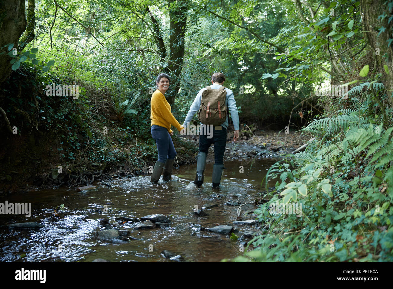 Hiker couple walking in stream Stock Photo - Alamy