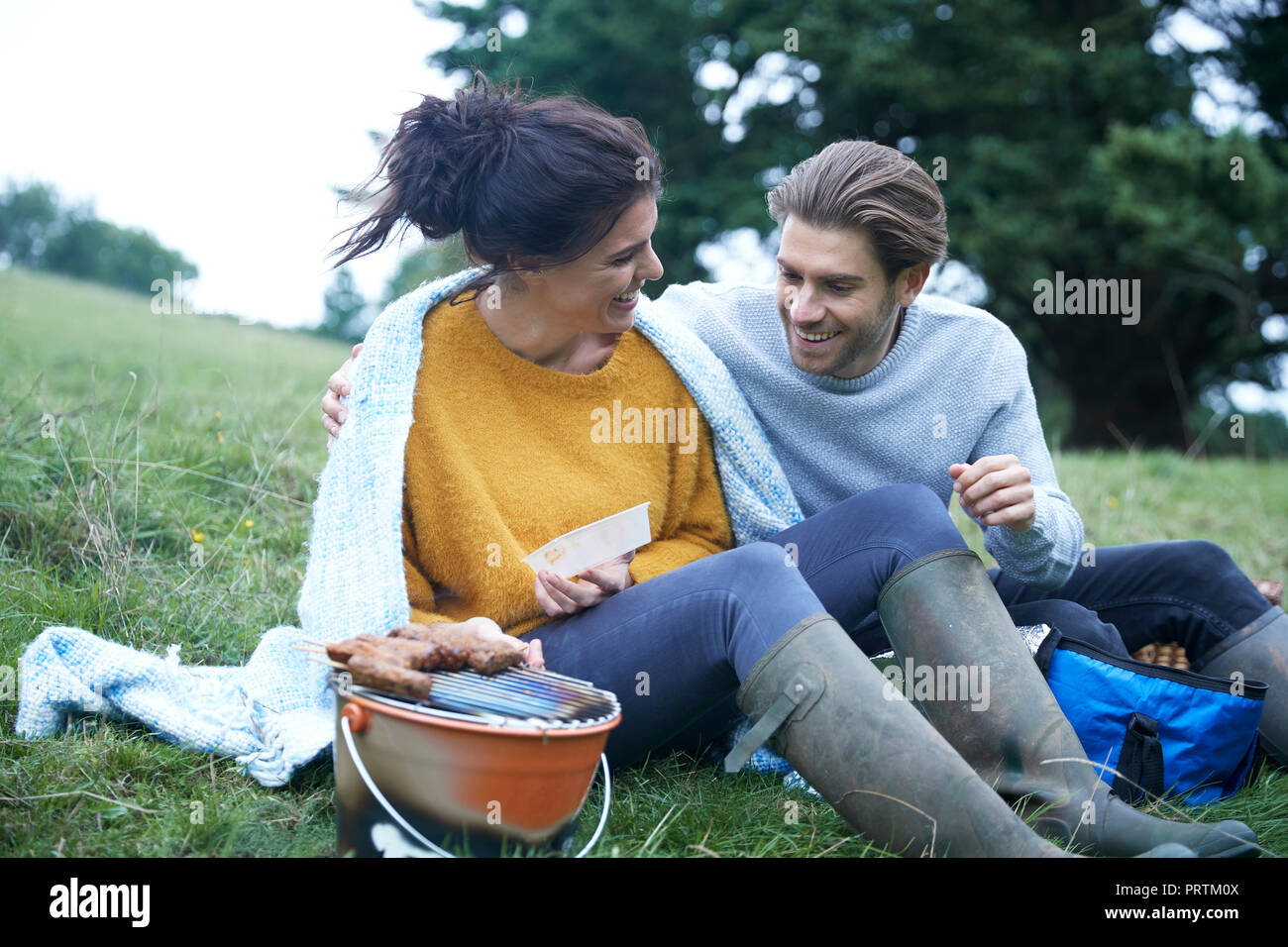 Couple sitting in rural field cooking on barbecue grill Stock Photo - Alamy