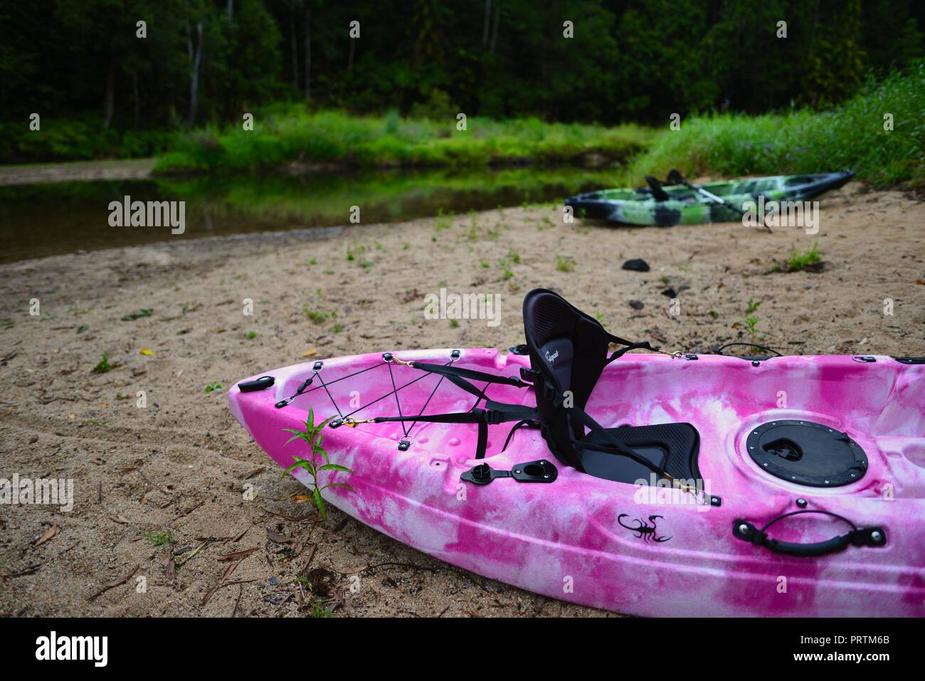 Pink sit on top kayak on the sand next to a river, no people, South ...
