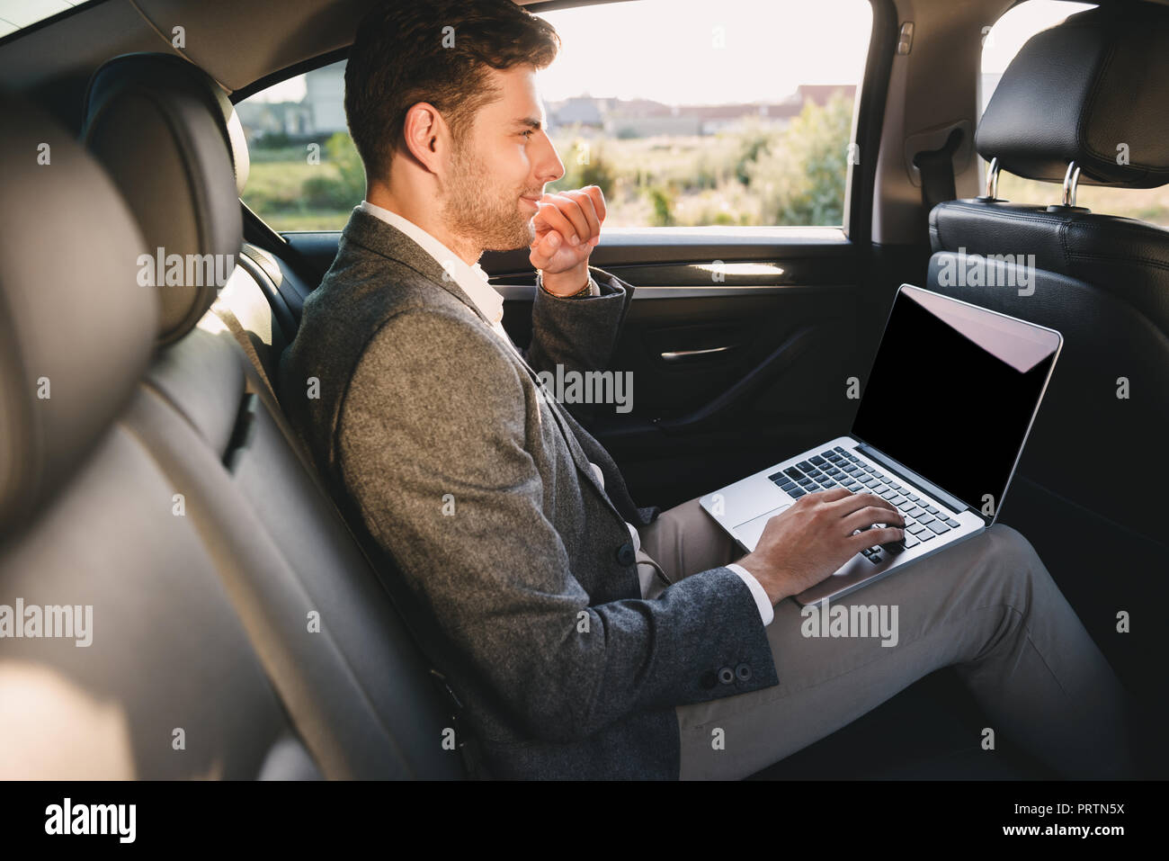 Portrait of handsome man in suit working on laptop while back sitting ...