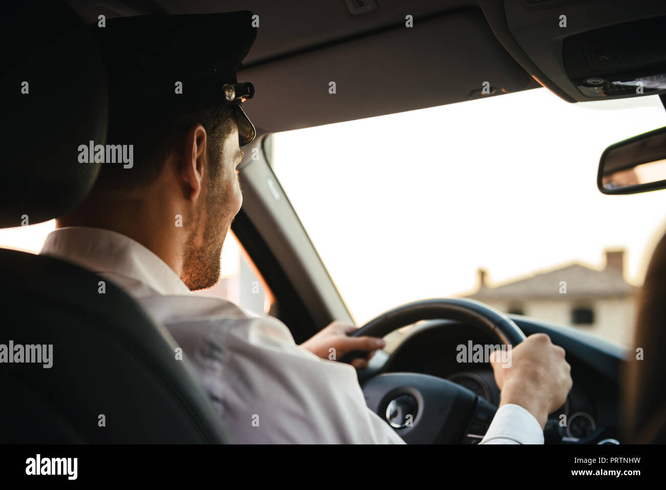 Portrait from back of caucasian chauffeur man wearing uniform and cap ...