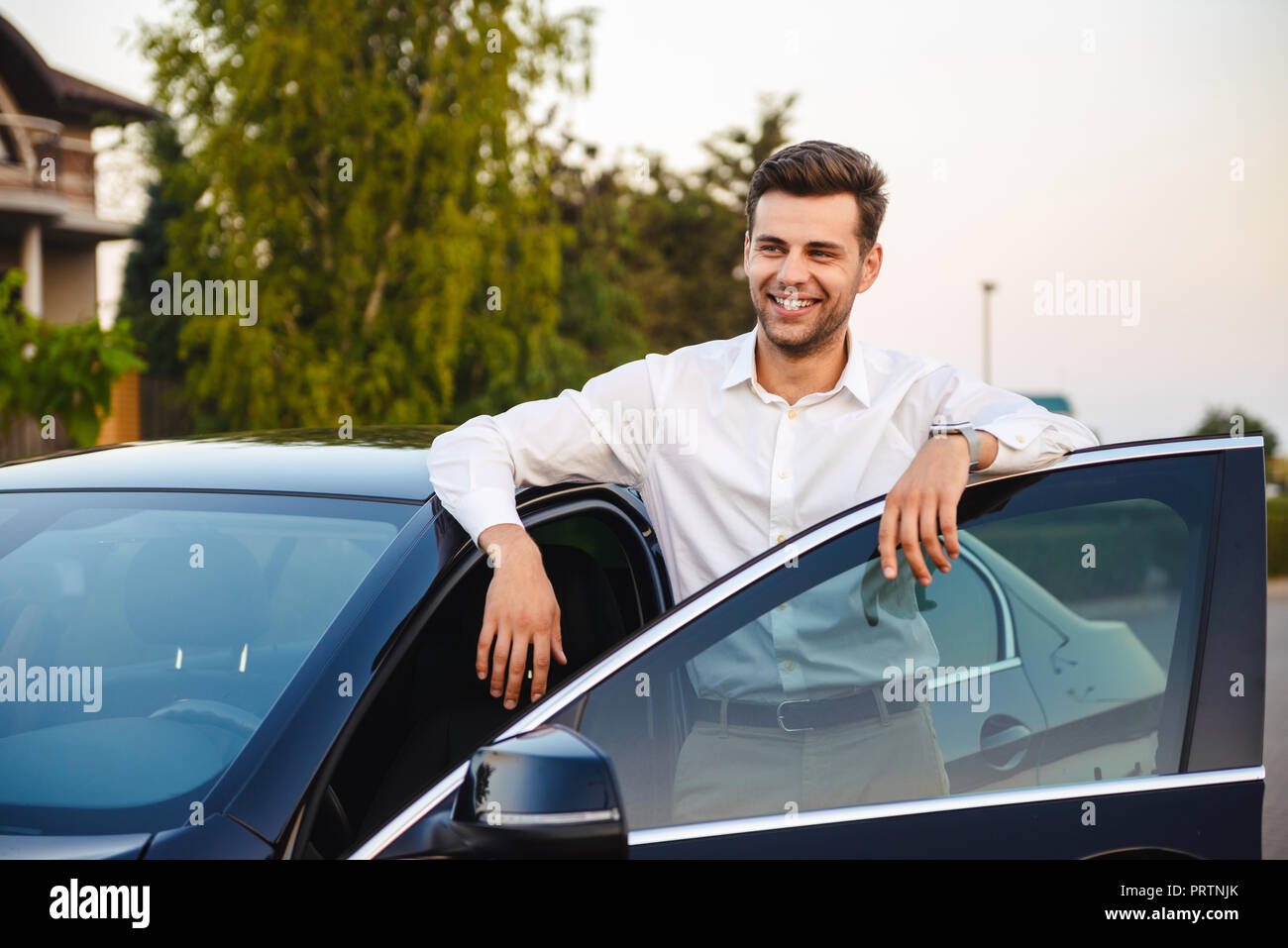 Portrait of handsome businesslike man wearing suit standing near his ...