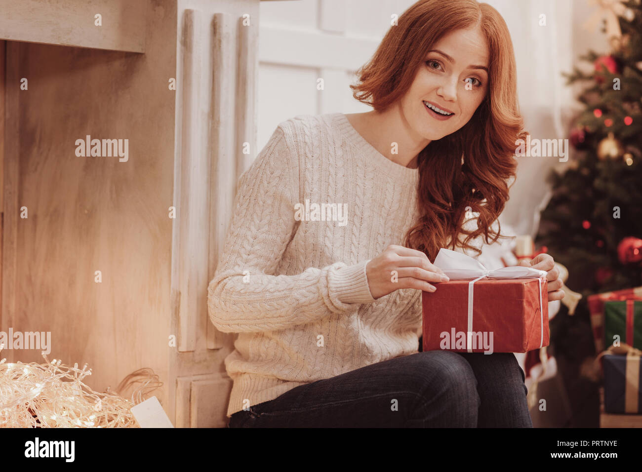 Positive young woman opening a box with present Stock Photo - Alamy