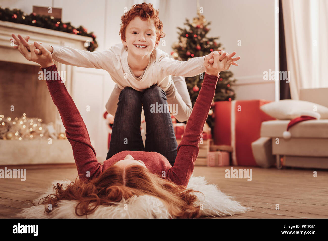Positive mother holding a child in flying position Stock Photo - Alamy