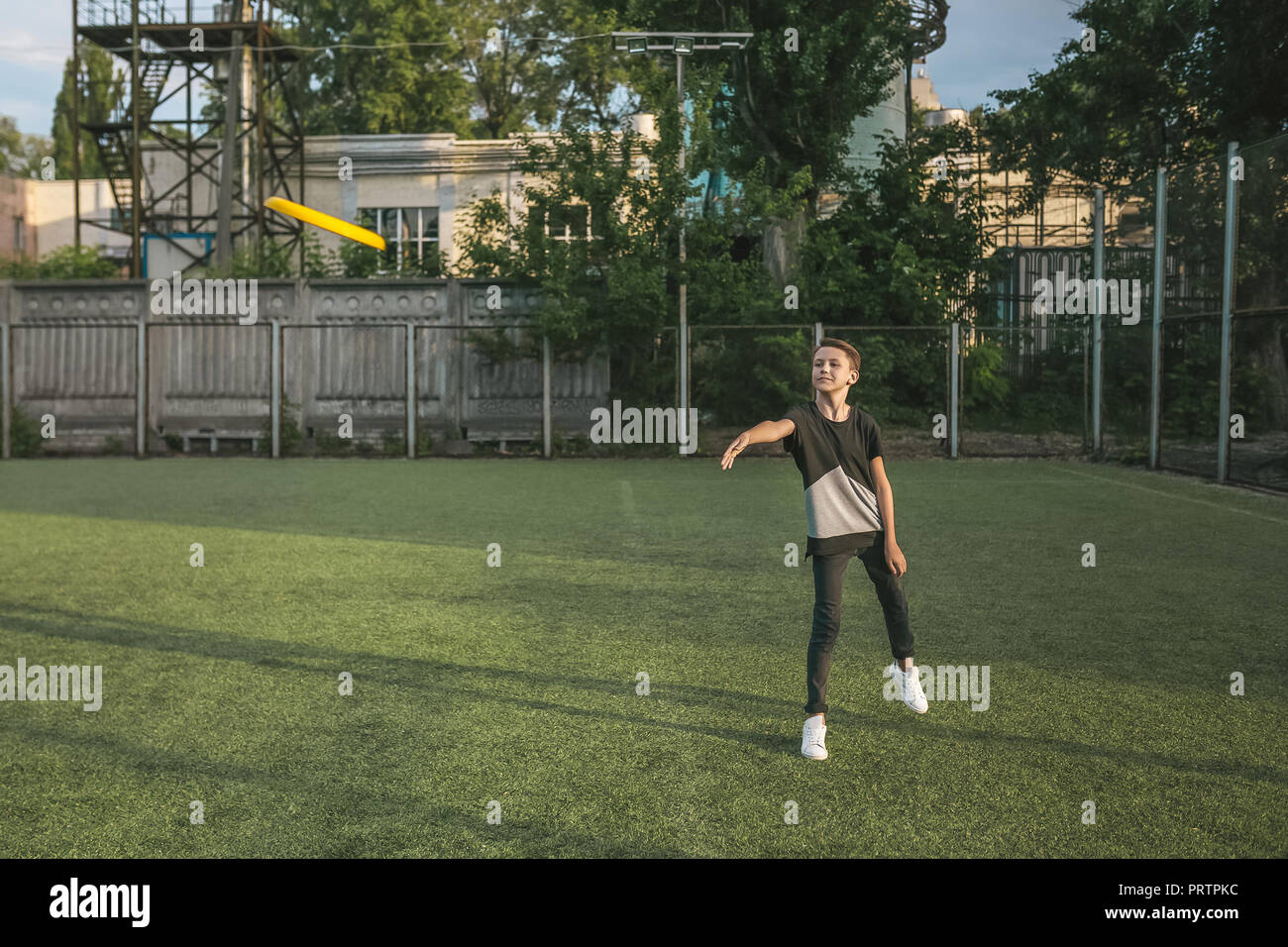 full length view of boy throwing flying disc on green lawn Stock Photo ...
