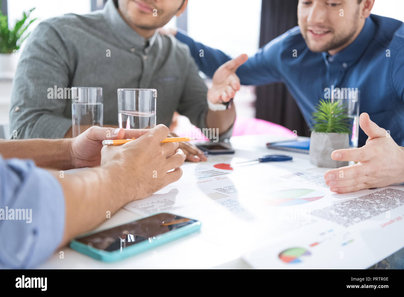 Smiling young businessmen drinking water and discussing new project ...