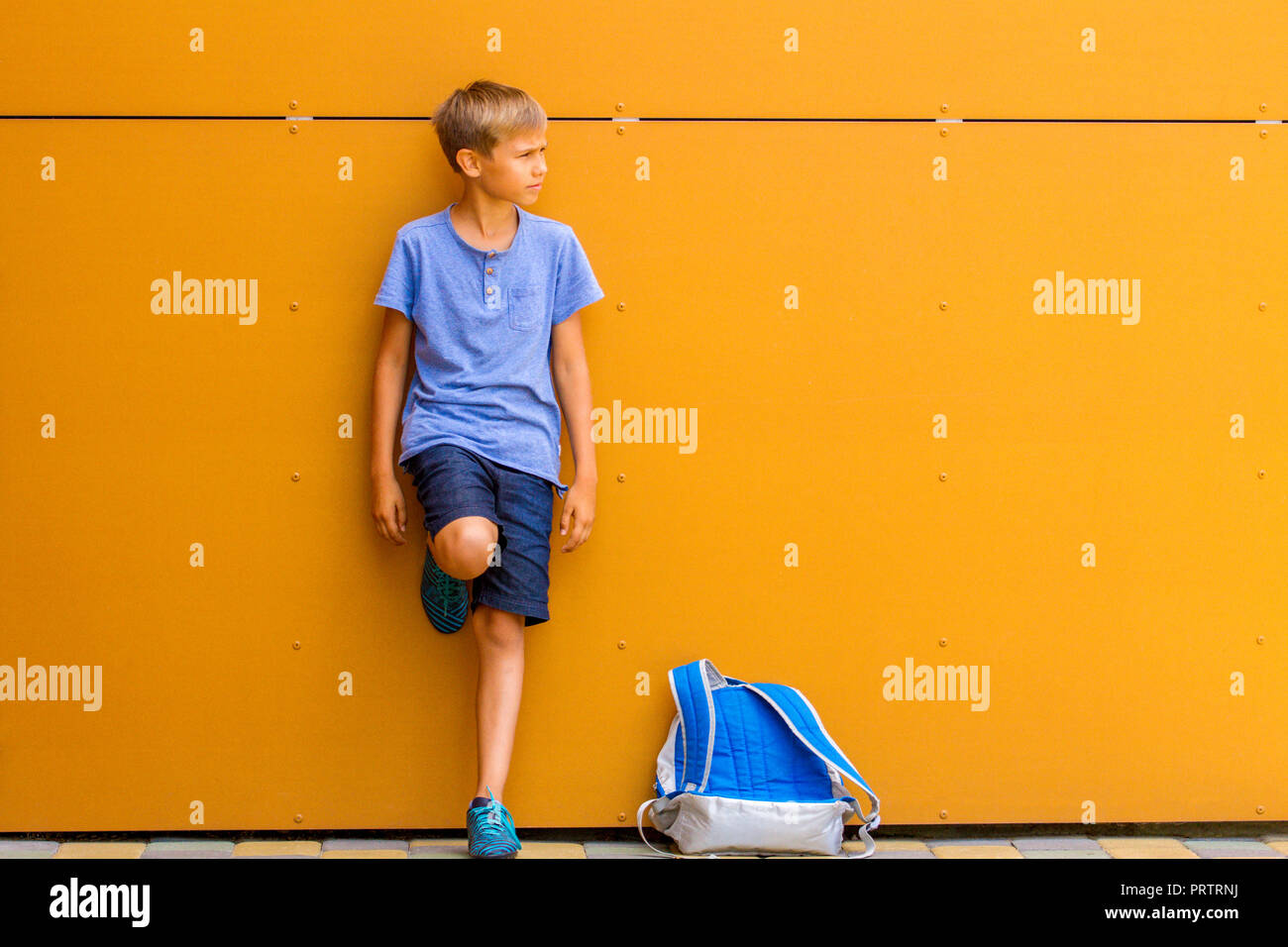 Boy stands near colorful wall background and looks away Stock Photo - Alamy