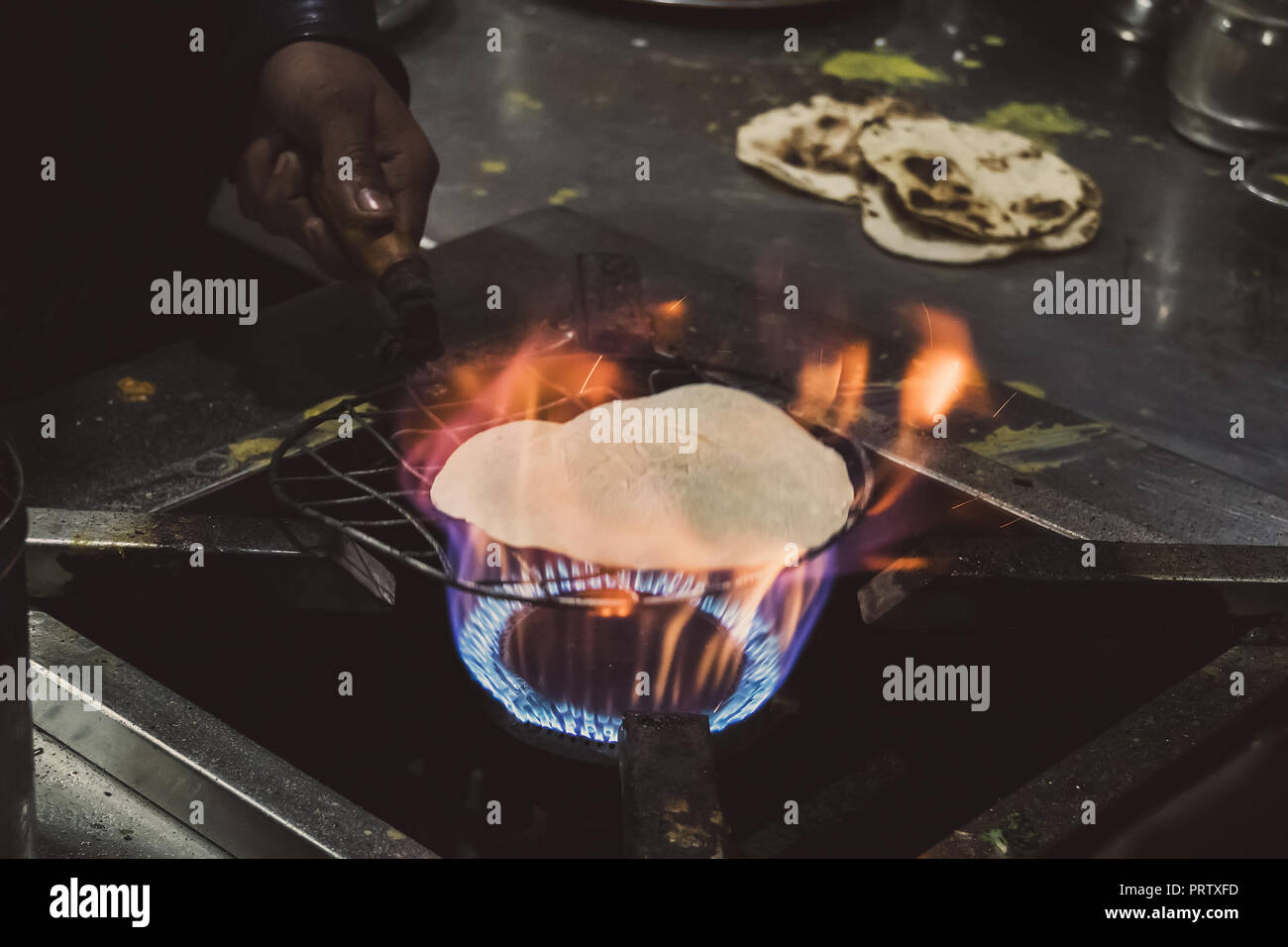 A roti indian flatbread cooking on a coal fire. Bread cake is fried on ...