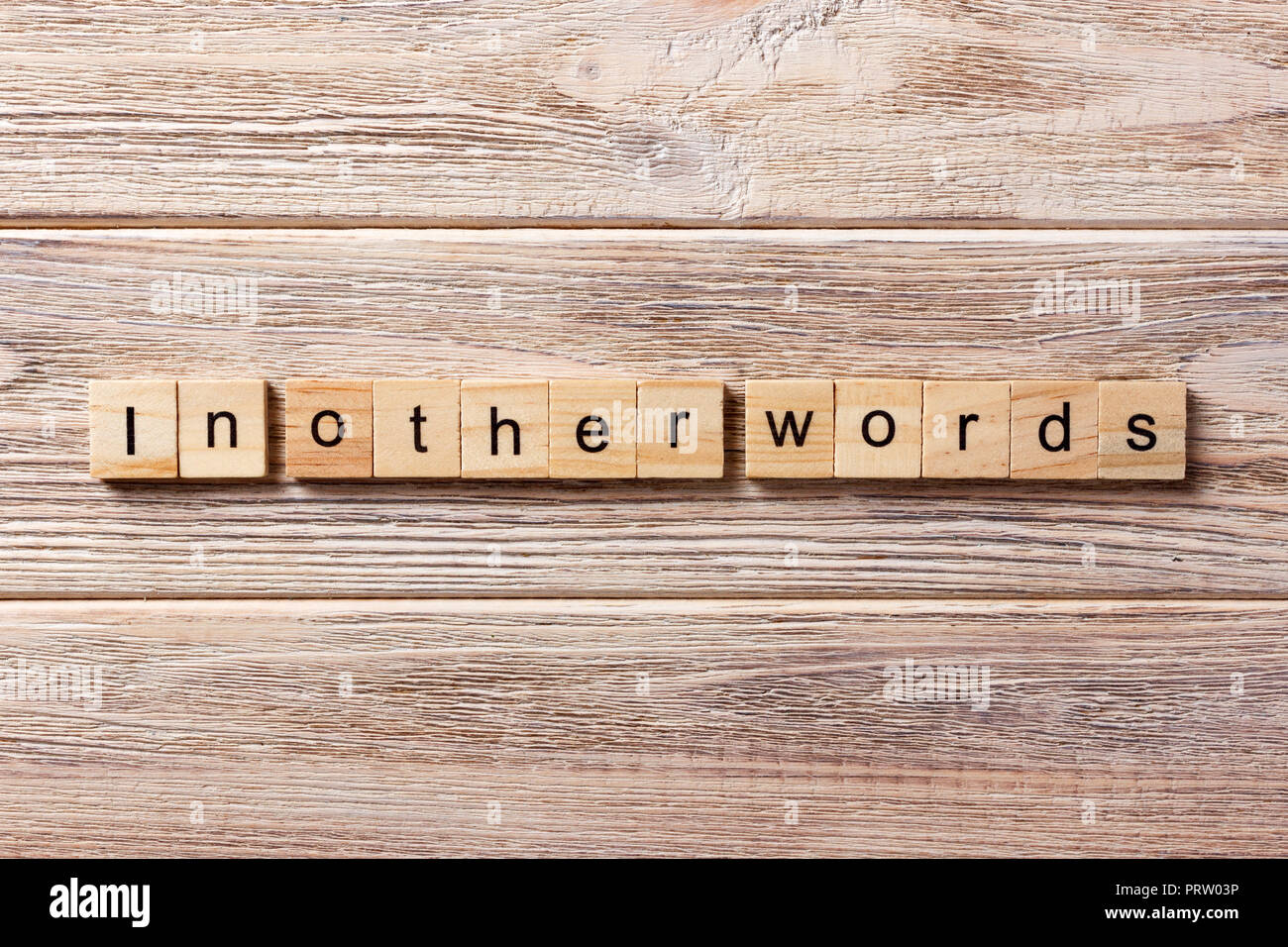 in other words word written on wood block. in other words text on table ...
