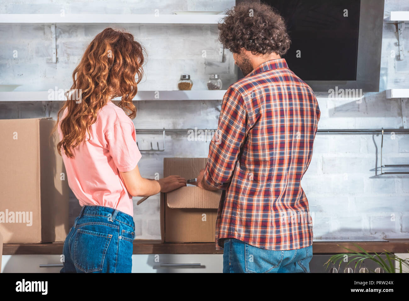 back view of couple unpacking cardboard box in new kitchen Stock Photo ...