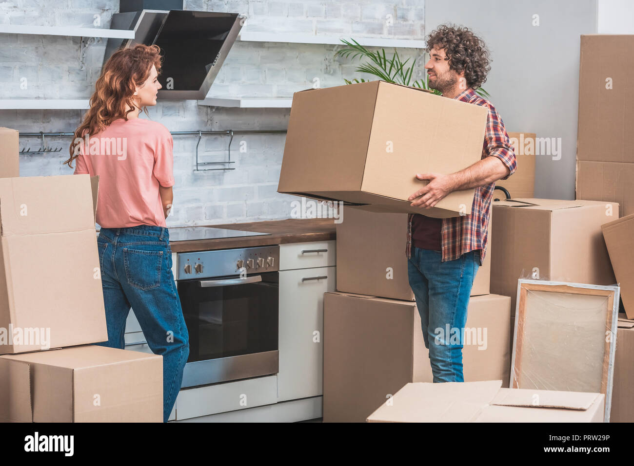 couple unpacking cardboard boxes together at new kitchen Stock Photo ...