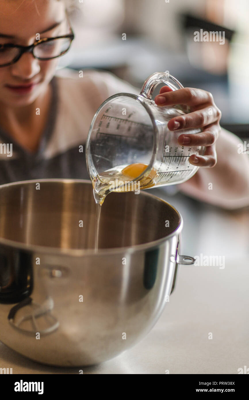 Girl pouring egg yolk into mixing bowl for christmas cookies at kitchen ...