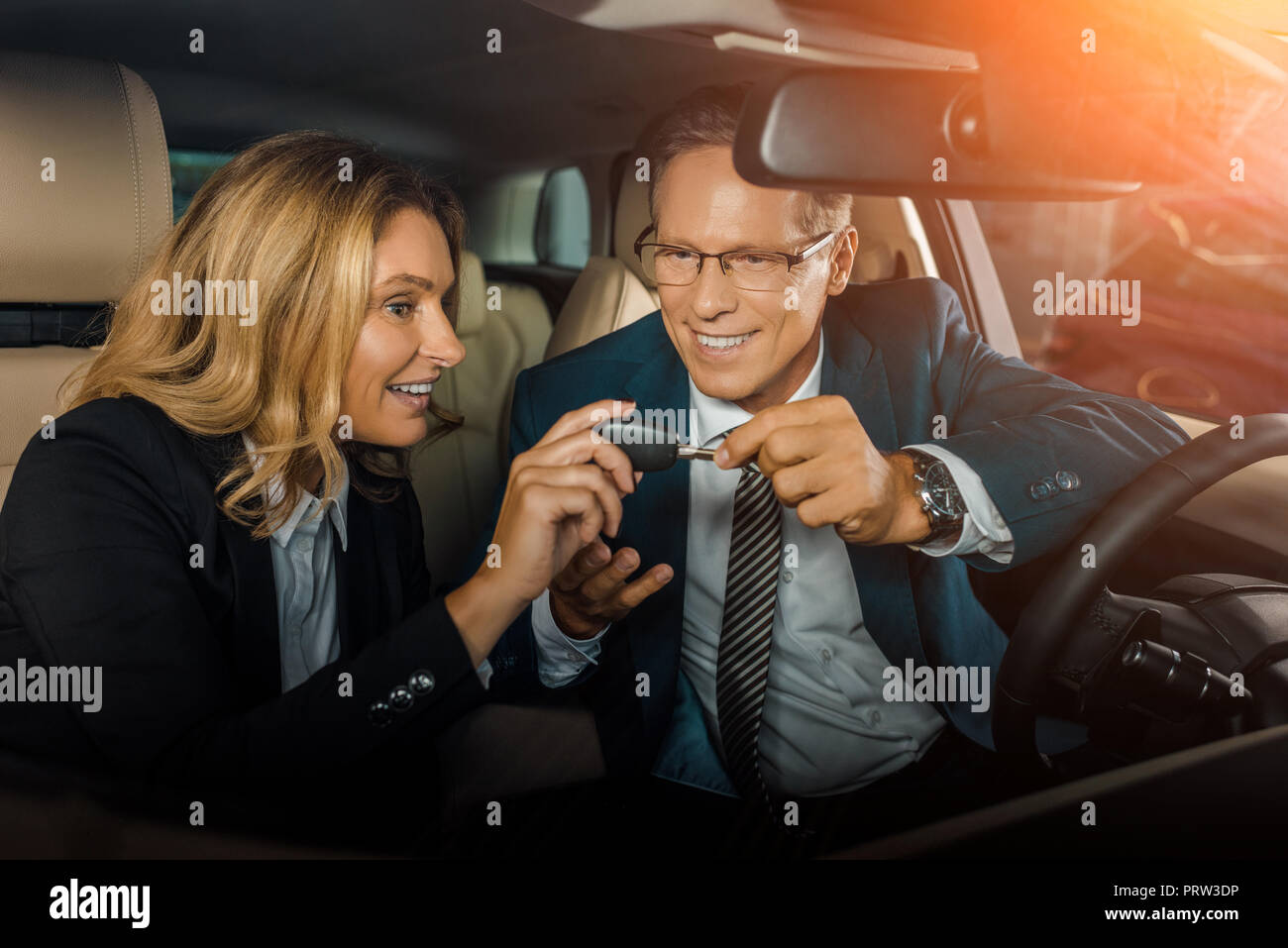 couple in formal wear with car key sitting in new car for test drive ...