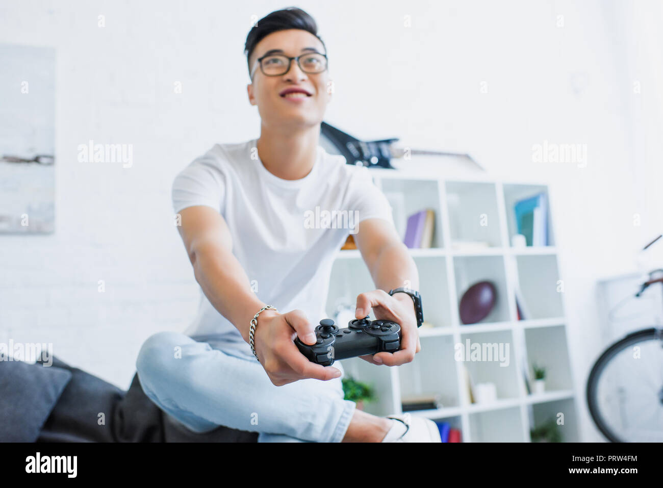selective focus of happy handsome asian man playing video game on sofa ...