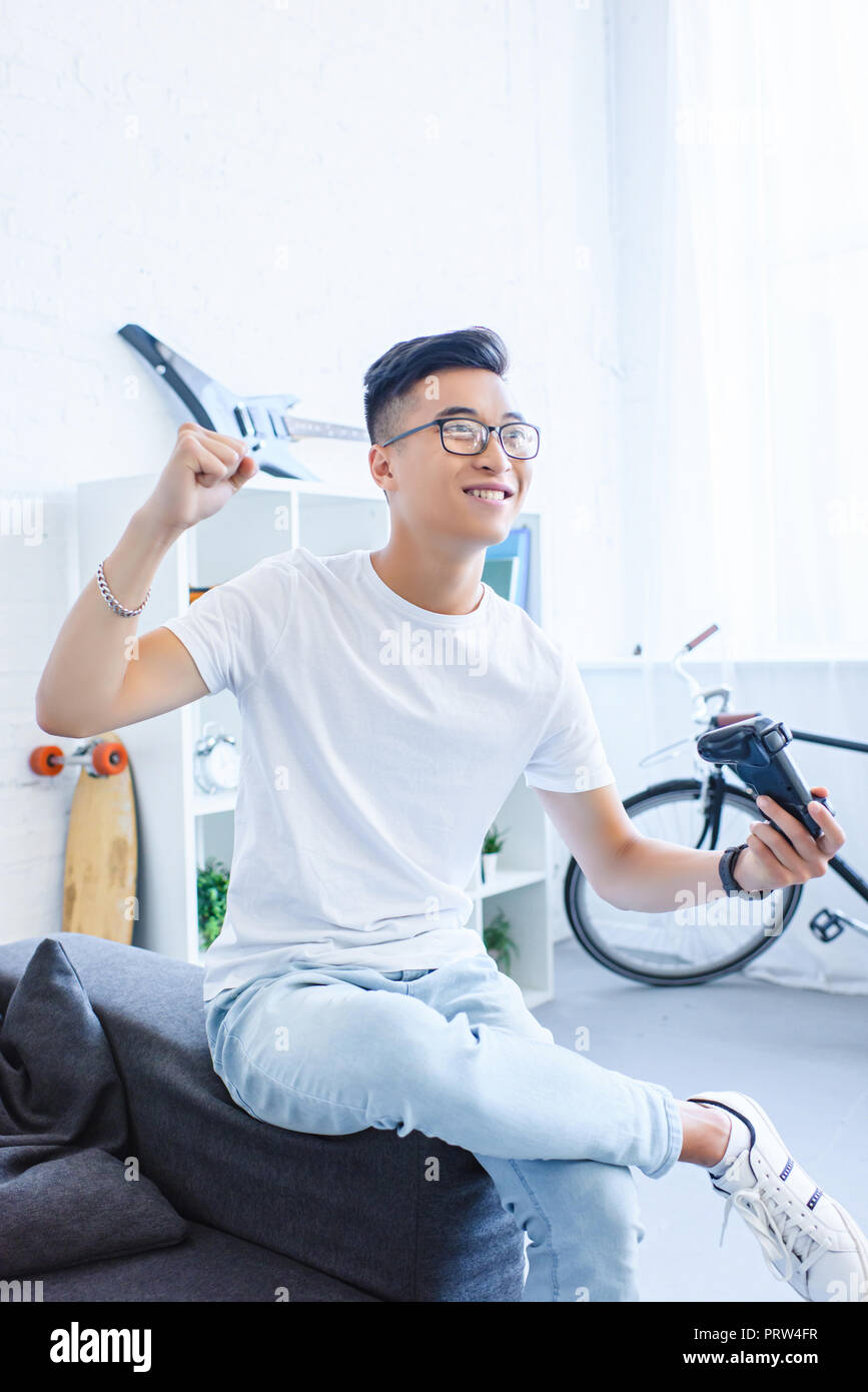 happy handsome asian man playing video game and showing yes gesture at ...