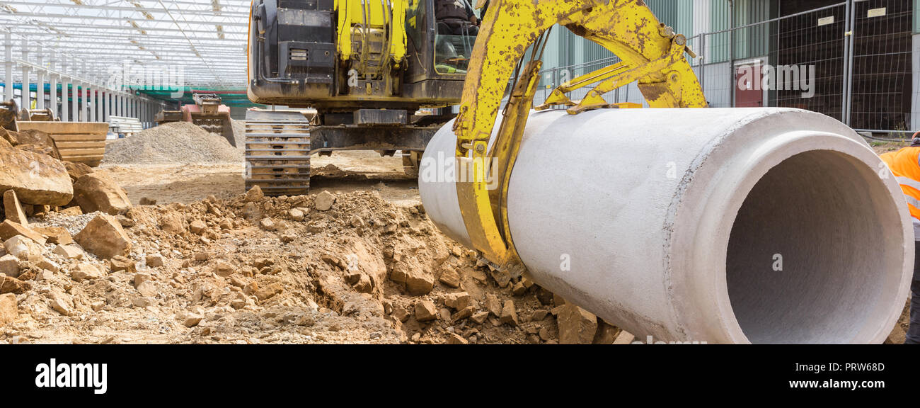 construction site excavator with a concrete pipe Stock Photo - Alamy
