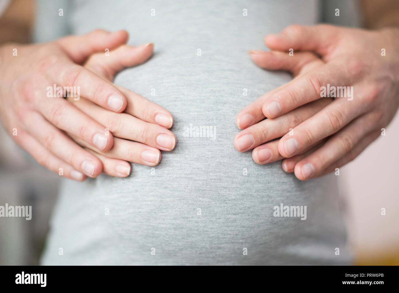 Close Up Of Male And Female Hands Resting On Pregnant Womans Stomach ...