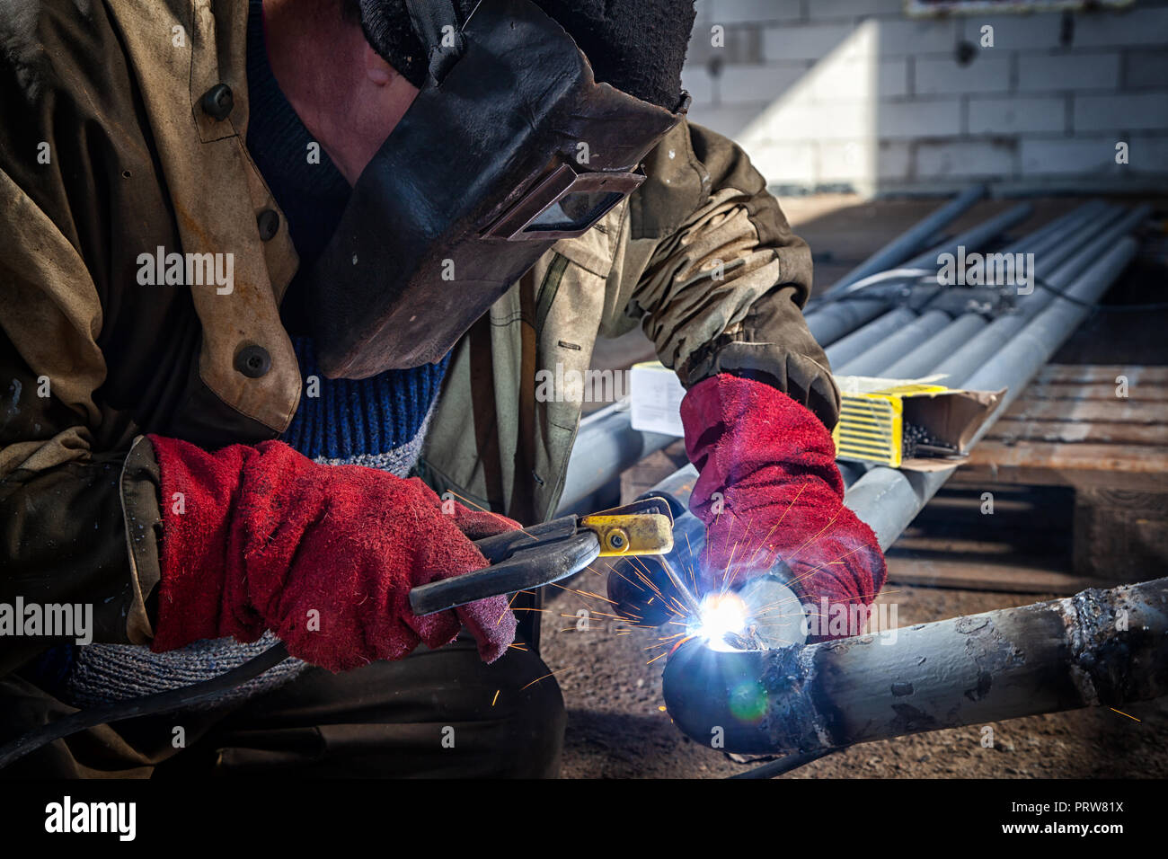 Close up welder weld metal pipe at construction site. A builder in ...