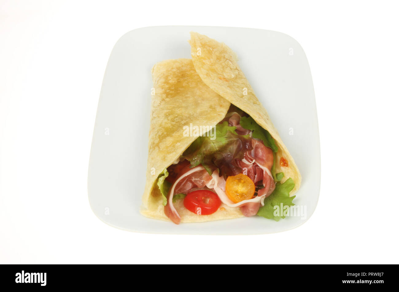 Parma ham and salad piada wrap on a plate isolated against white Stock ...
