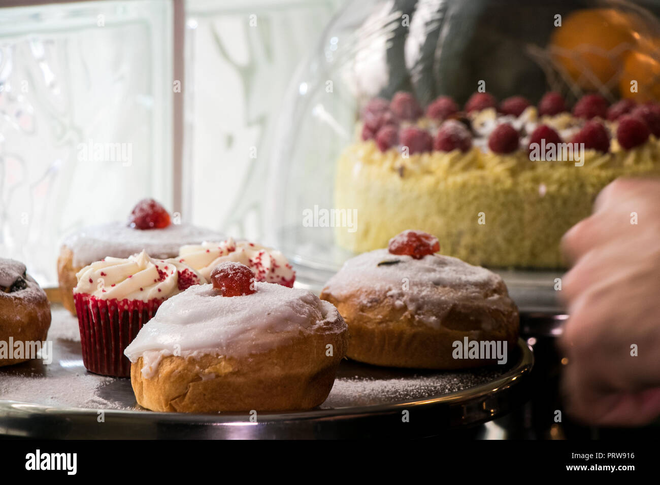 Cakes on cakestand with icing and cherries with glass window in ...