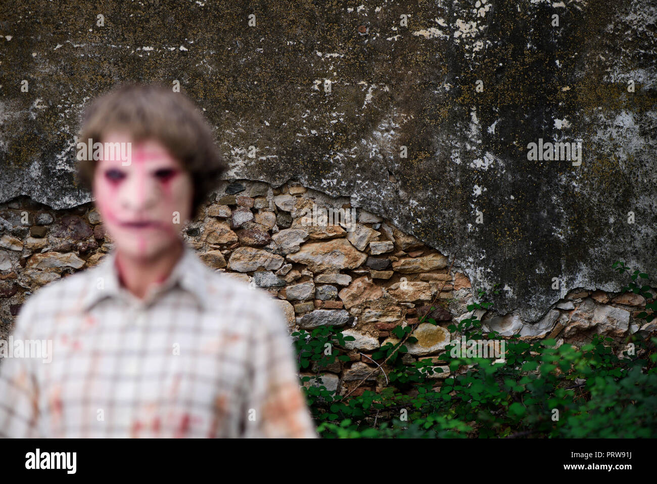 an intentionally unfocused scary disfigured man, wearing dirty and ...