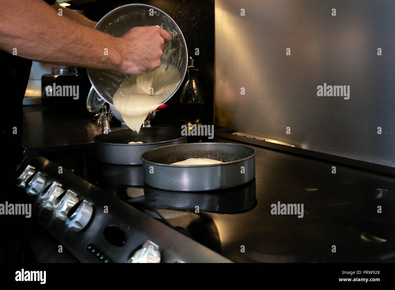 Muscle strong arms of male chef, baker spoon our cake mixture into ...