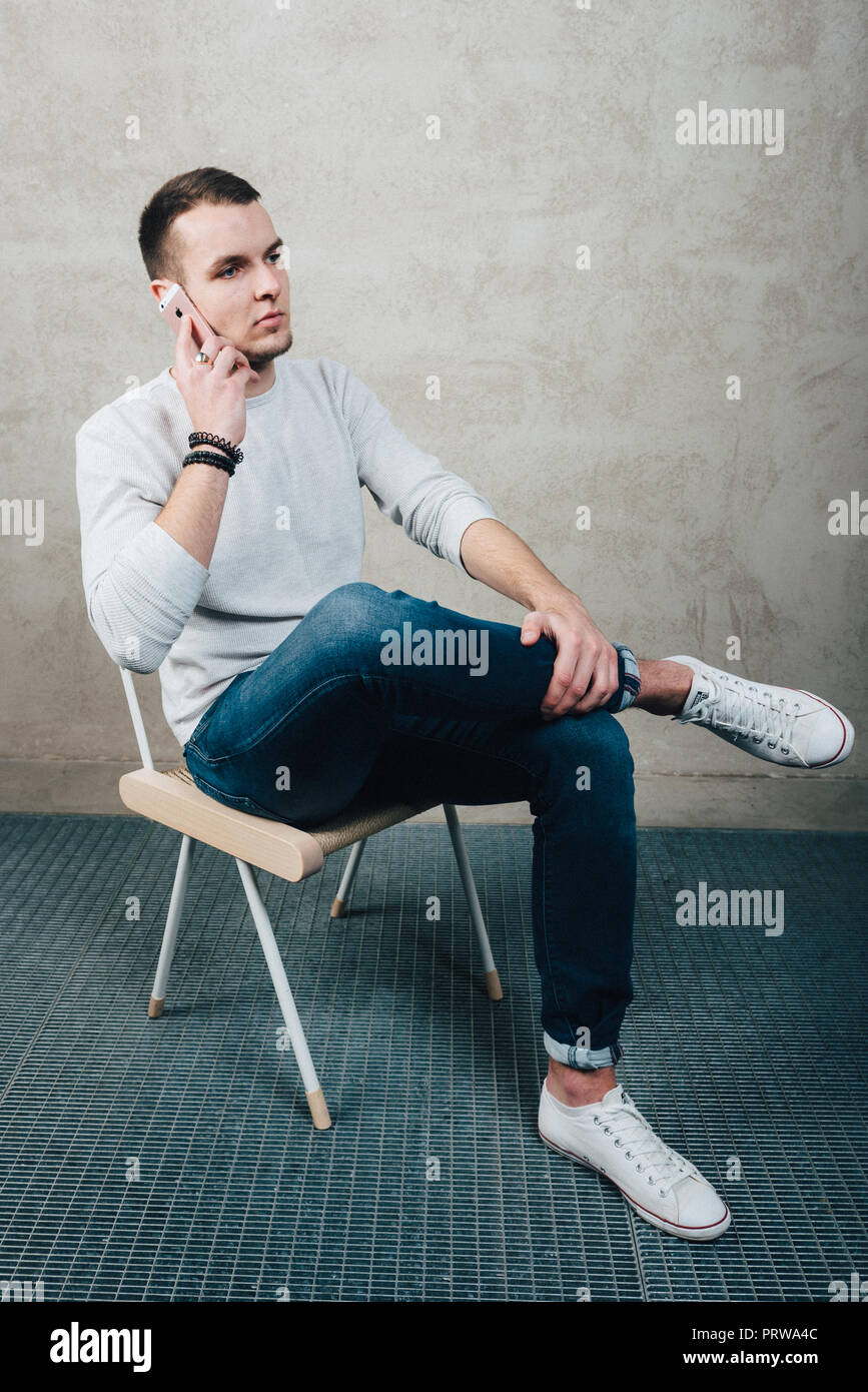 Man sitting on a chair with legs crossed talking on his phone Stock ...