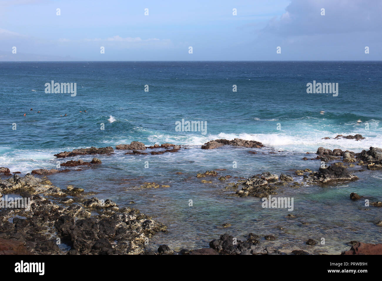Surfers swimming out into the Pacific Ocean from Hookipa Beach to catch ...