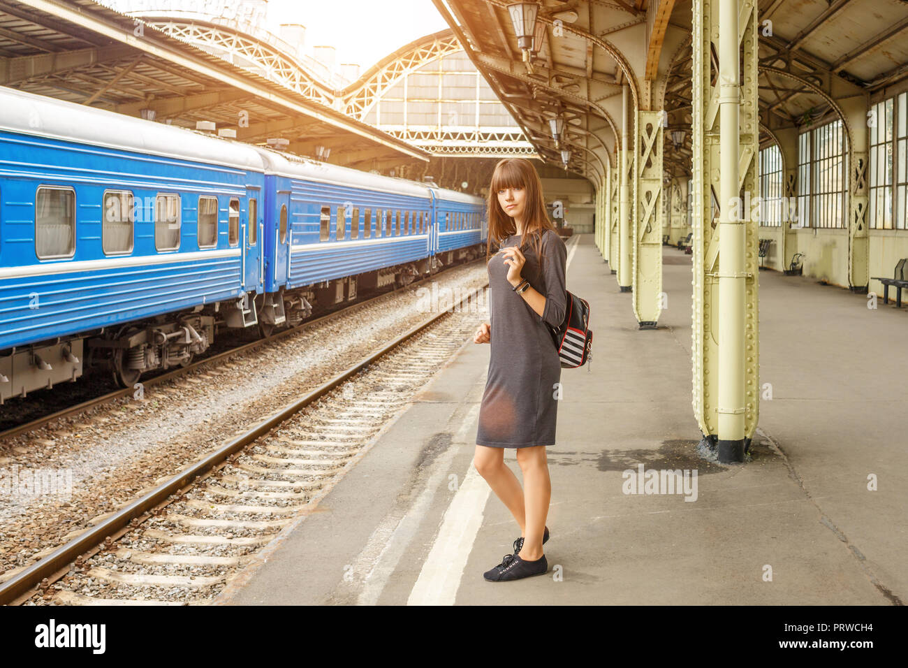 beautiful young woman standing on the platform of the railway station ...