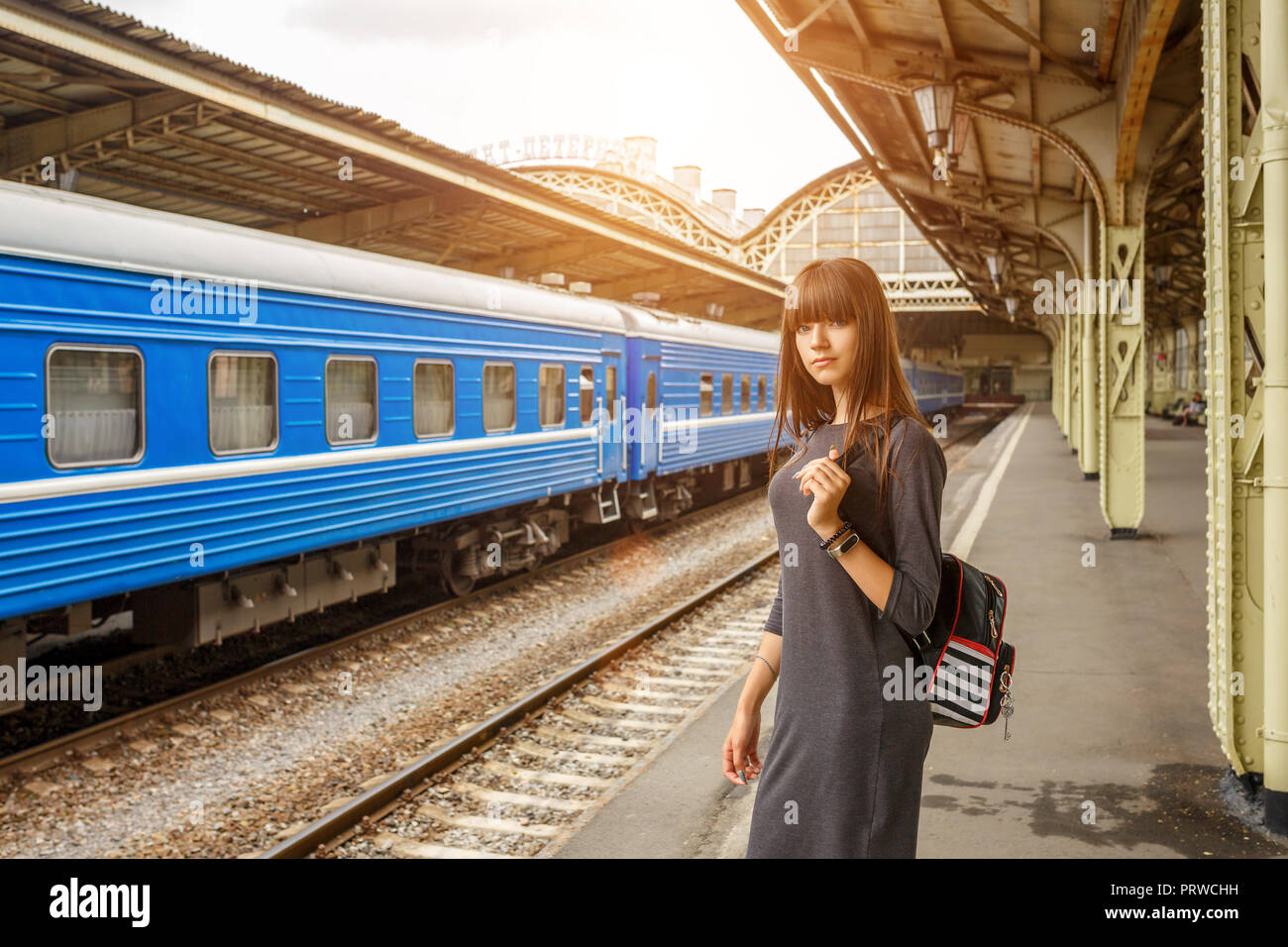 beautiful young woman standing on the platform of the railway station ...