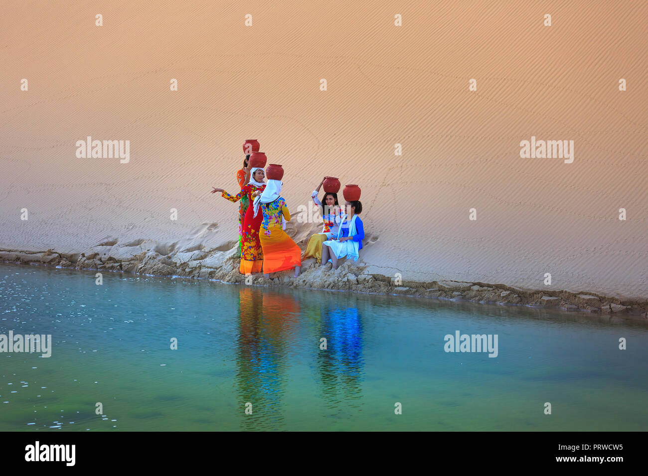 Cham women in traditional dress walking across sand dunes to collecting ...