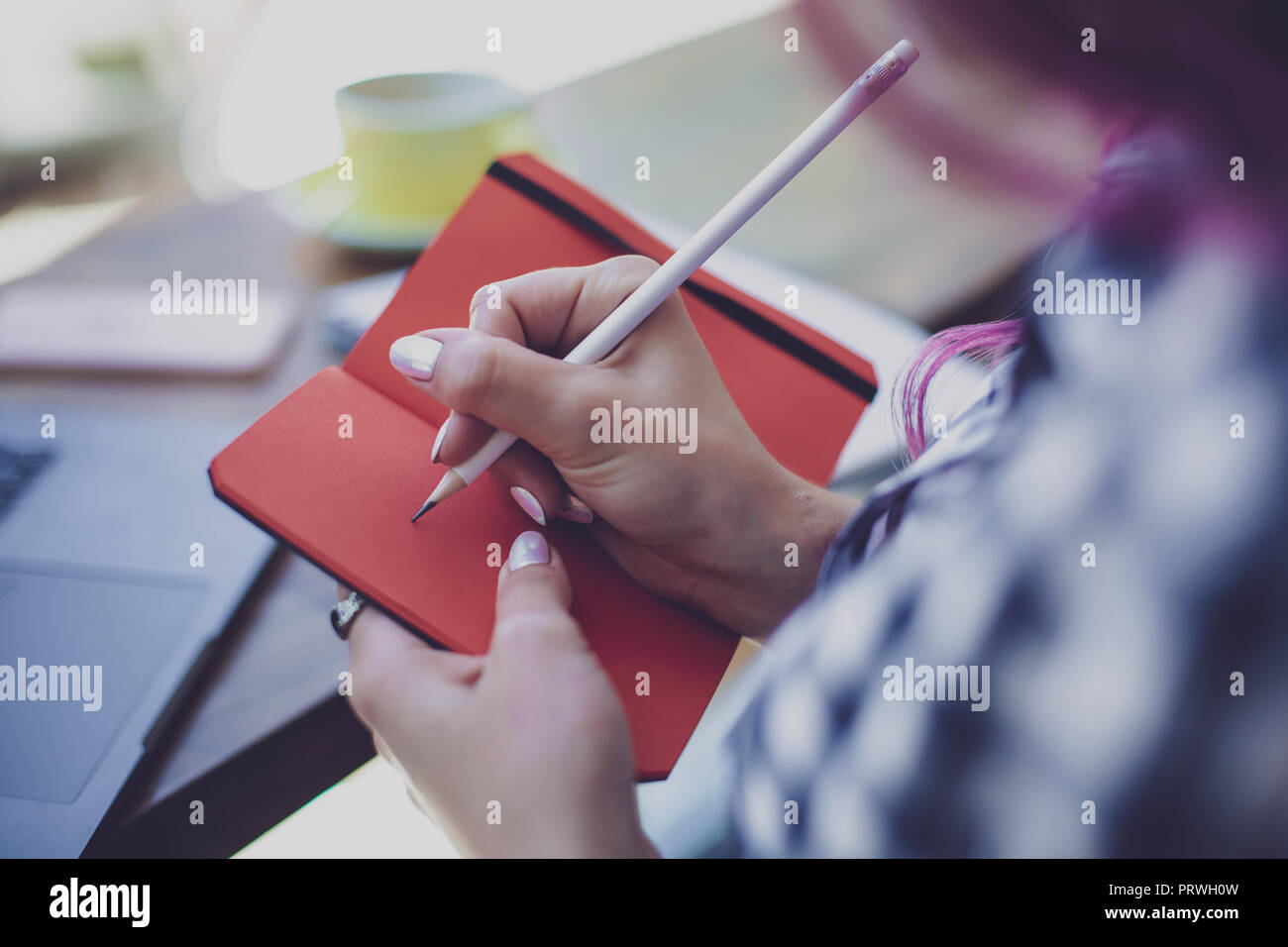 Positive female student with pink hair writing down funny story Stock ...