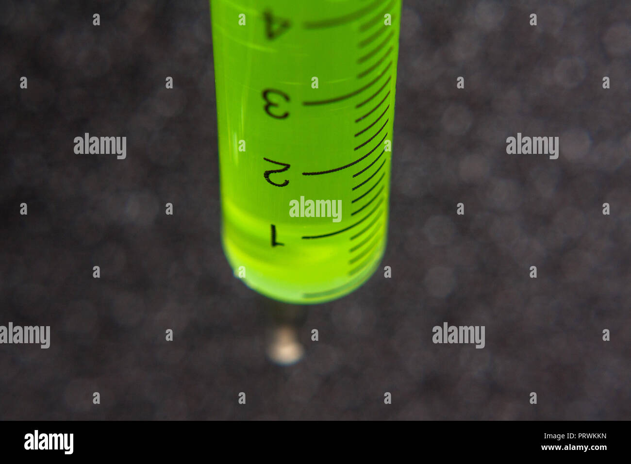 Medical syringe with green liquid on a black background Stock Photo - Alamy