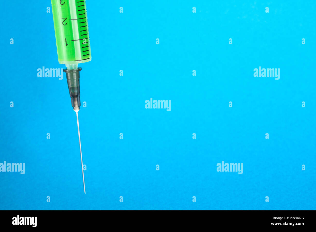 Medical syringe with green liquid on a blue background with space for ...