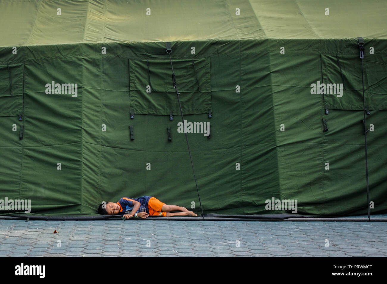 Palu, Indonesia. 4th Oct, 2018. A boy falls asleep beside the tent at ...