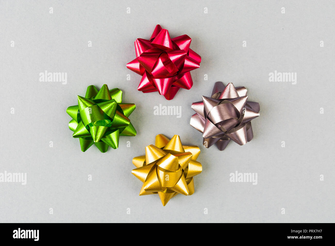 Four color festive bows in center over grey background Stock Photo - Alamy