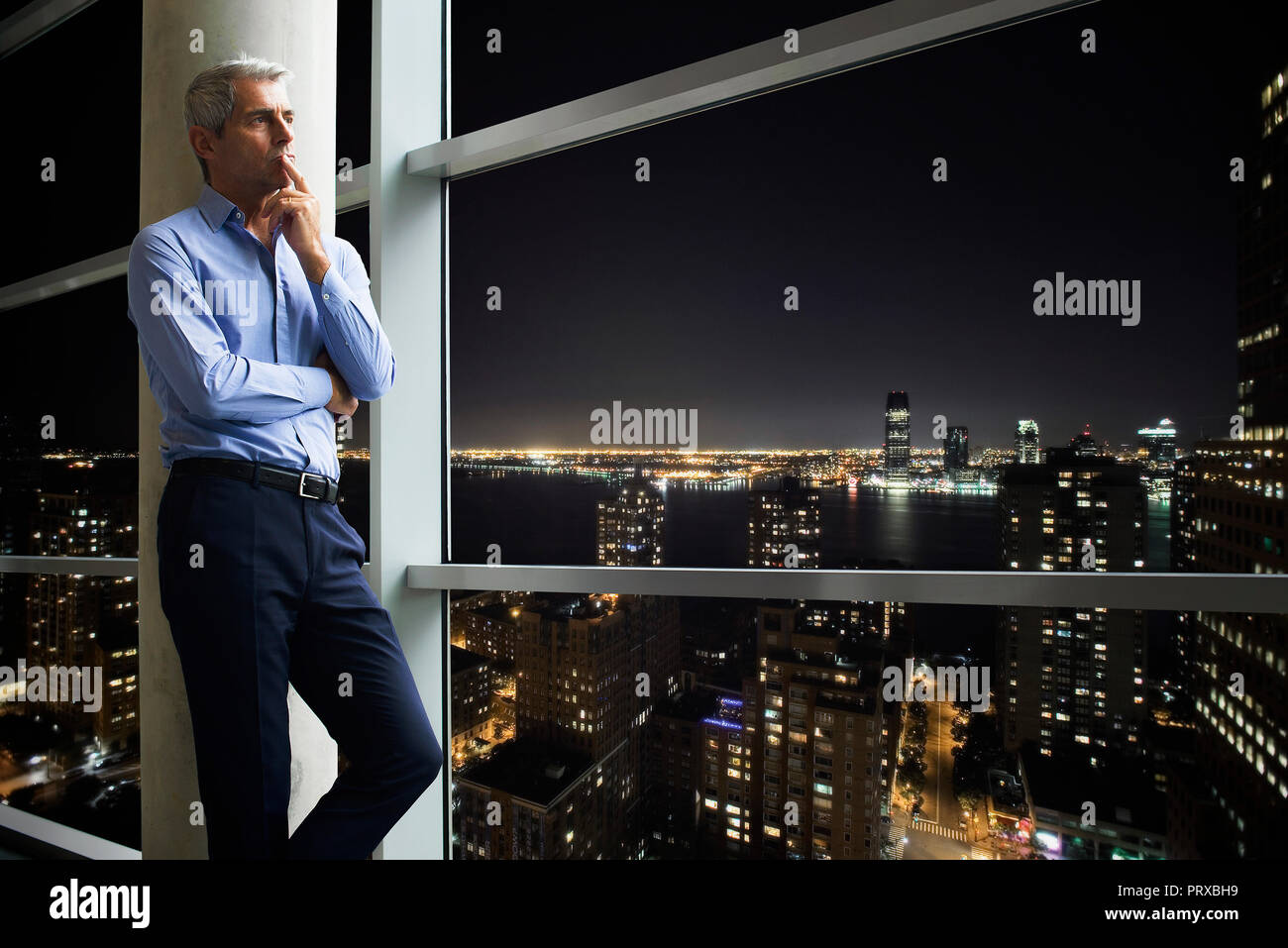 Businessman standing near window Stock Photo - Alamy