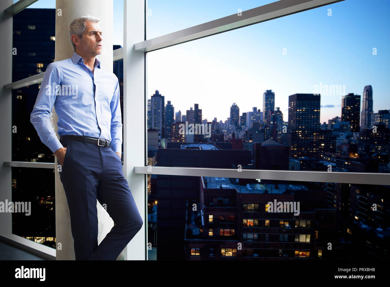 Businessman standing near window Stock Photo - Alamy
