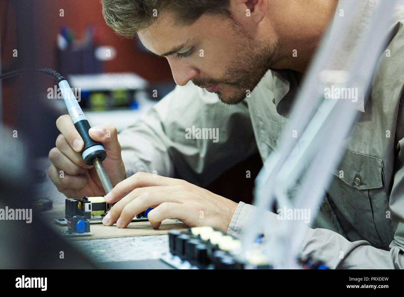 Engineer soldering circuit board in office Stock Photo - Alamy