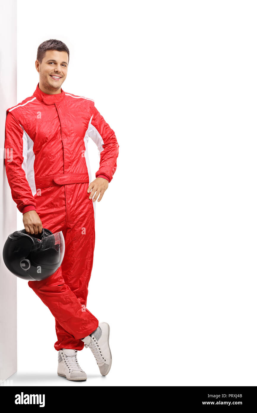 Full length portrait of a young male racer leaning on a wall isolated ...