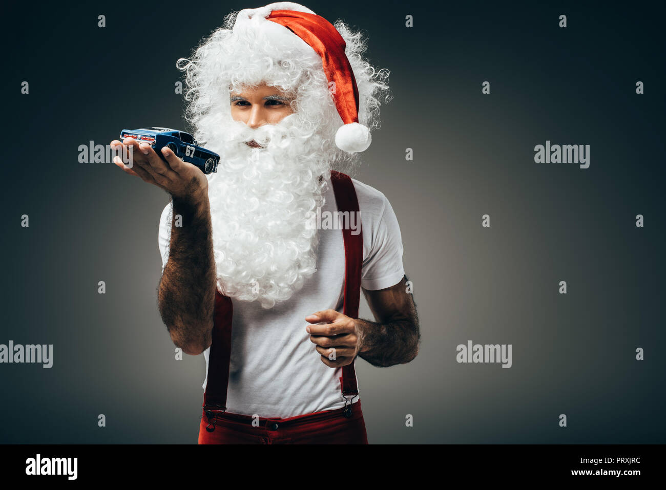 serious santa claus holding toy car on hand palm and standing isolated ...