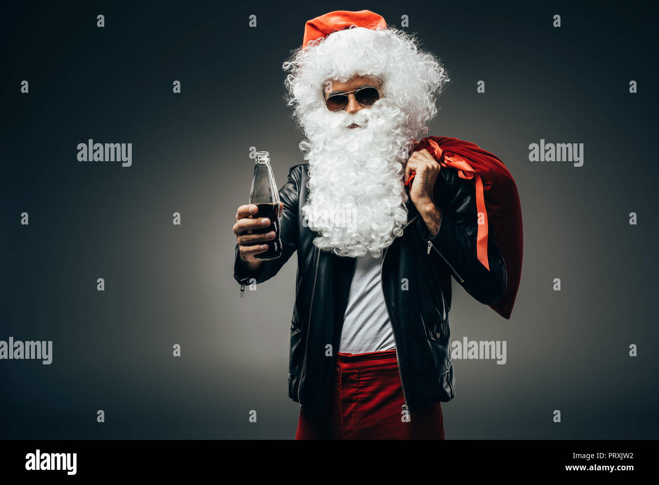 stylish santa claus in sunglasses and leather jacket showing bottle of ...