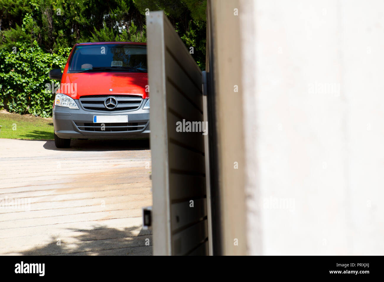 A red van parked on a drive behind an open garden gate in Spain Stock ...