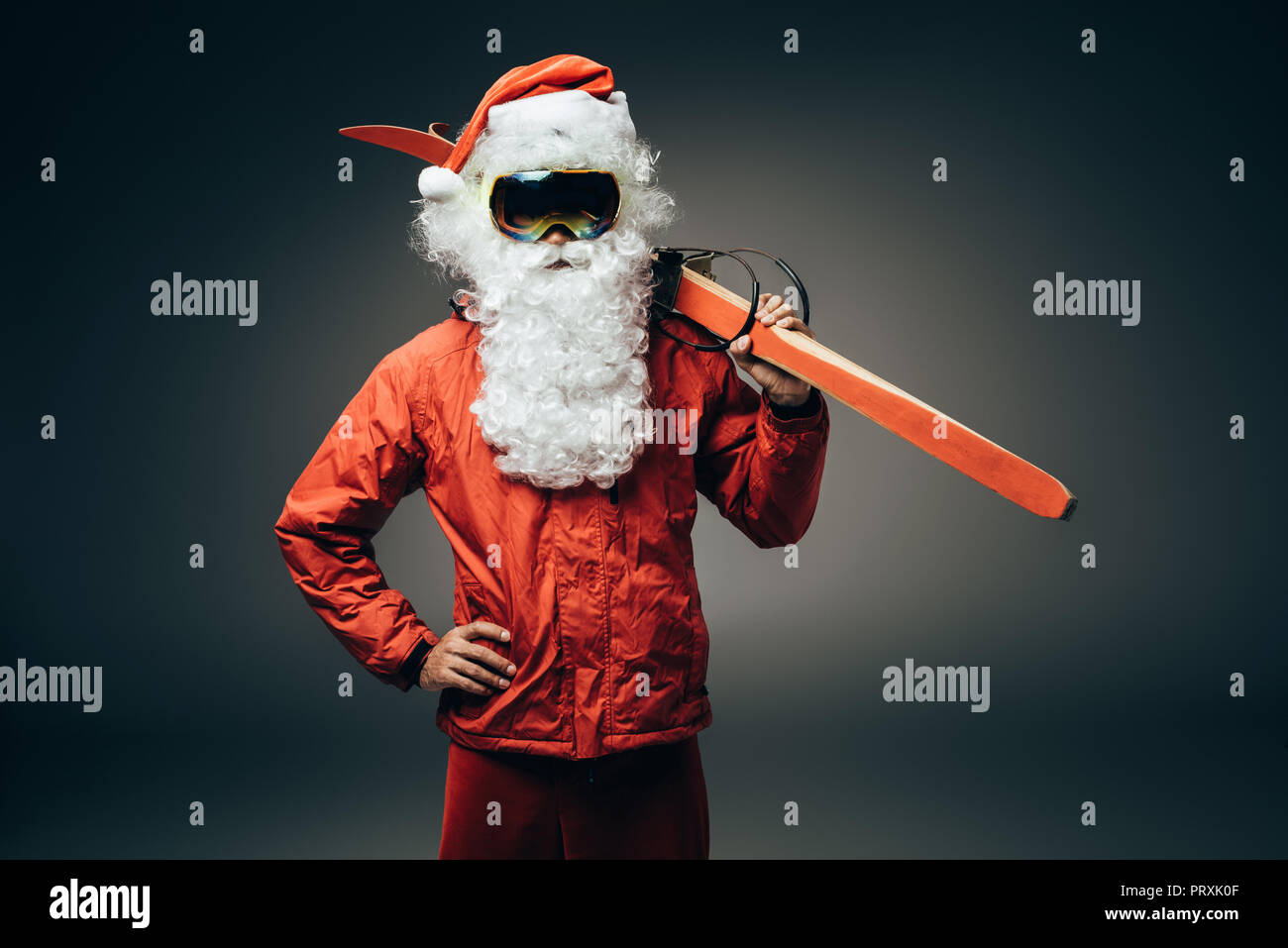 santa claus in ski mask and windbreaker holding skis over shoulder and ...