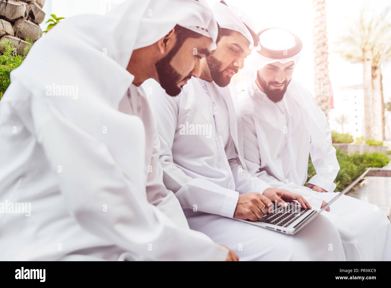 Three arabic men talking about business outddor Stock Photo - Alamy