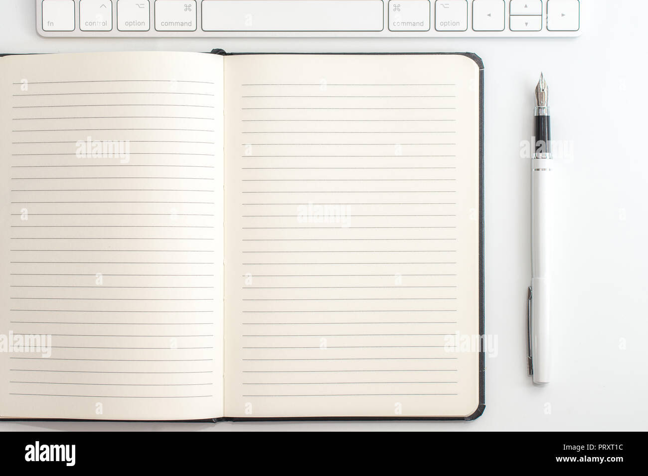 white table with notepad, keyboard and fountain pen. View from above ...